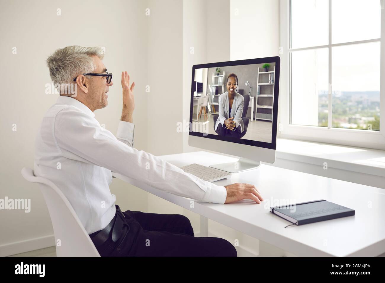 Man waving hello at the computer screen at the start of a virtual ...