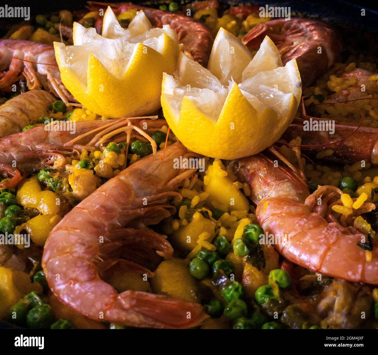 Chef cooking a paella bubbling with prawns, lemon and assorted seafood ...