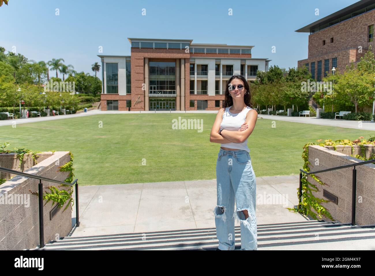 Confident female student on college campus standing with arms crossed ...