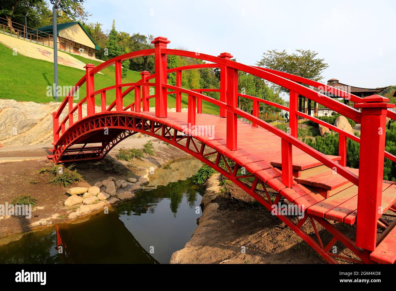 Old red wooden bridge across a small river in a green park. Vintage ...