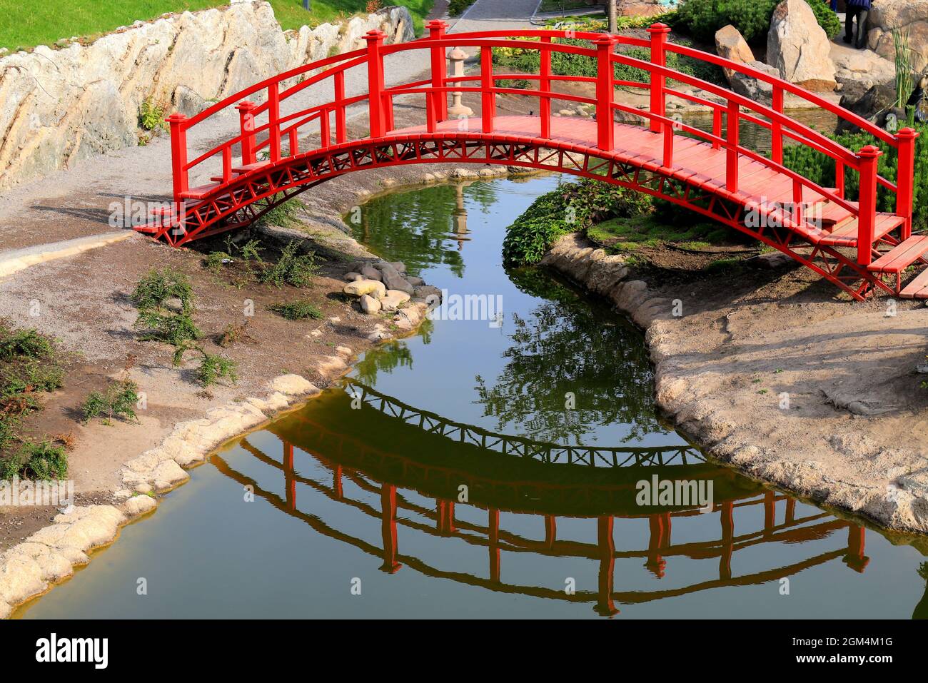 Old red wooden bridge across a small river in a green park. Vintage ...
