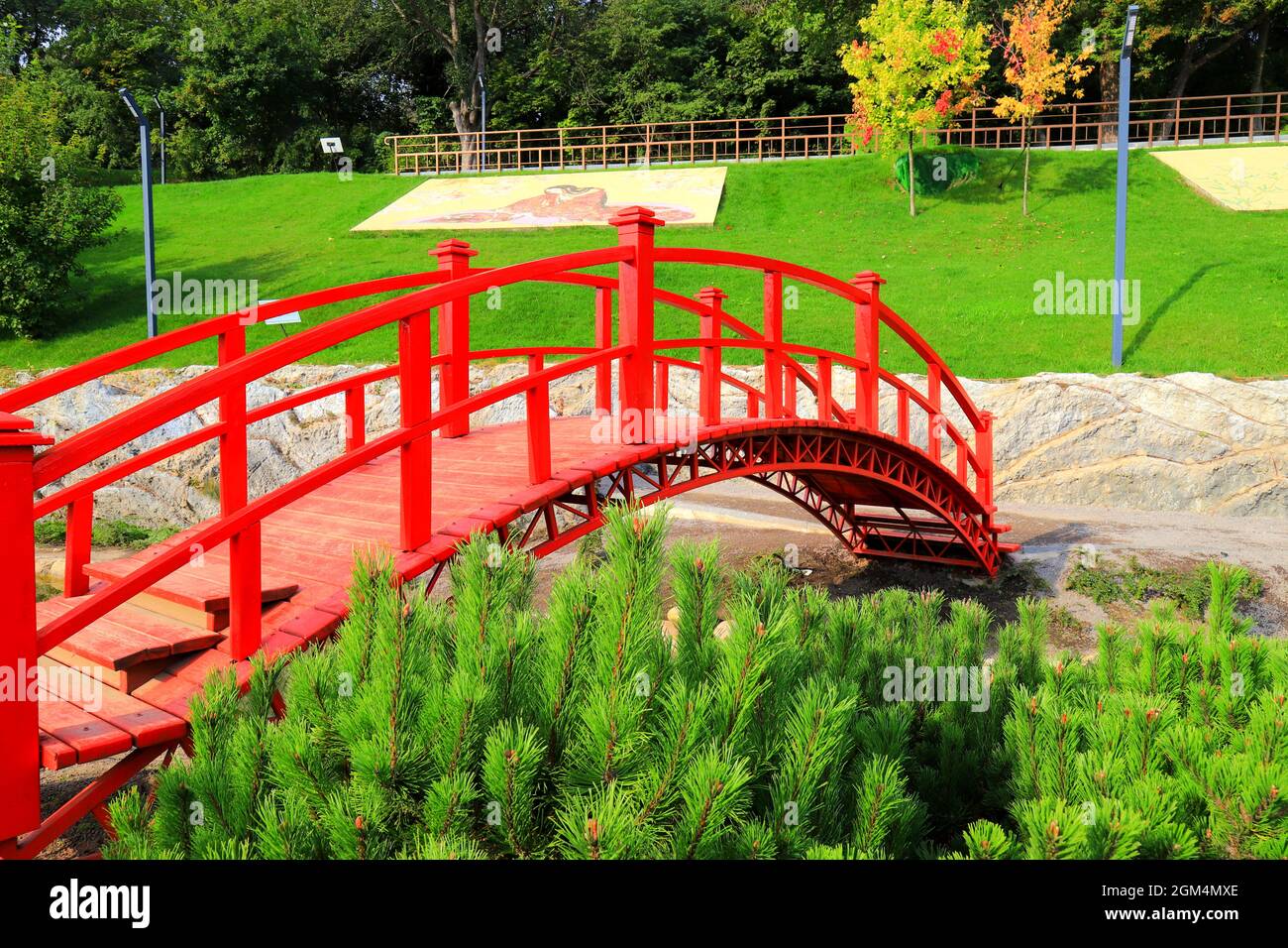 Old red wooden bridge across a small river in a green park. Vintage ...