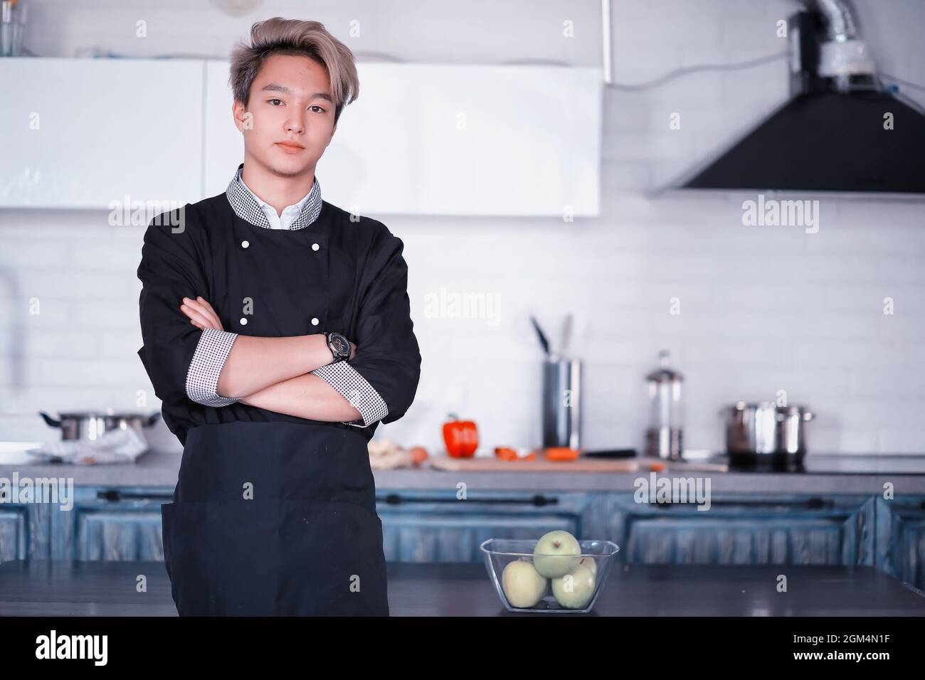 A young Asian cook in the kitchen prepares food in a cook suit Stock ...