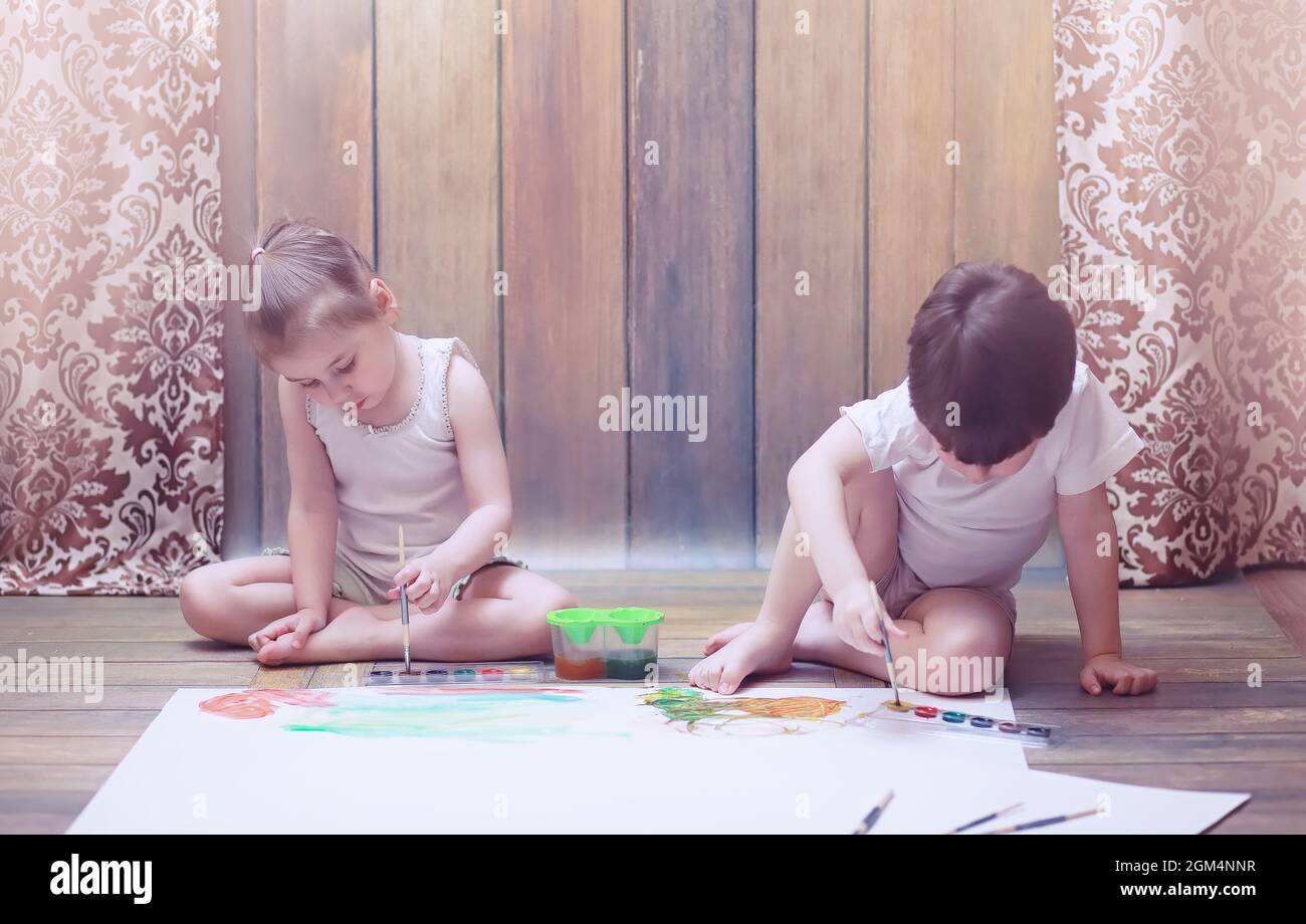 Little children paint on a large sheet of paper on the floor Stock ...