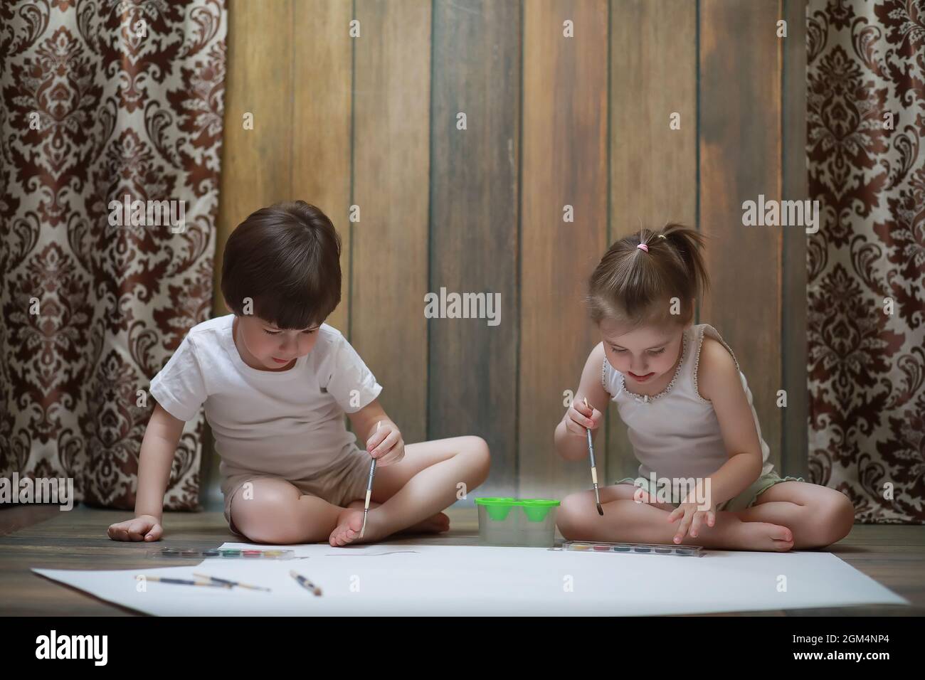 Little children paint on a large sheet of paper on the floor Stock ...