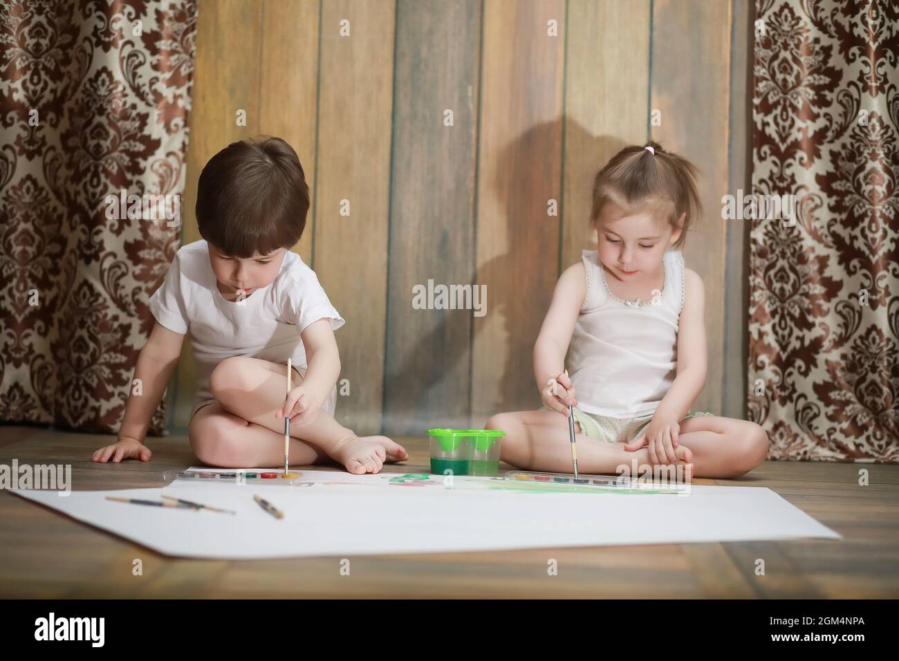 Little children paint on a large sheet of paper on the floor Stock ...