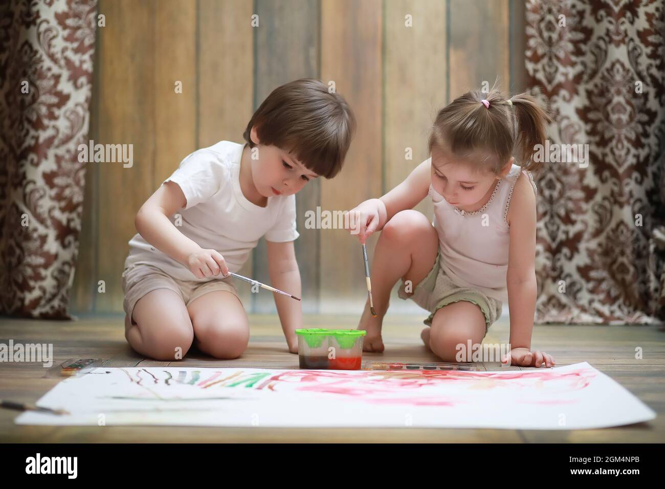 Little children paint on a large sheet of paper on the floor Stock ...
