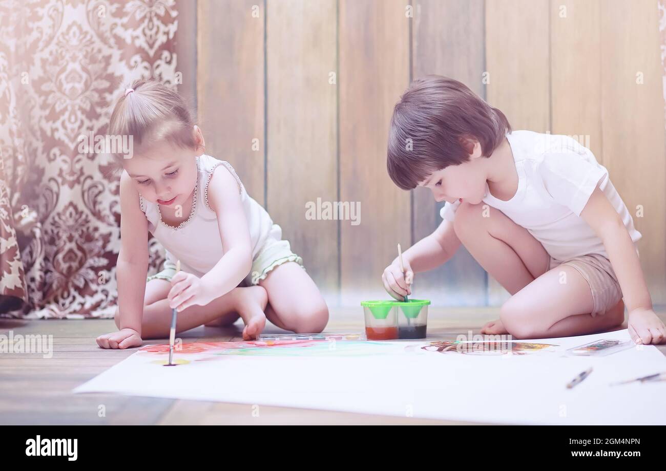 Little children paint on a large sheet of paper on the floor Stock ...