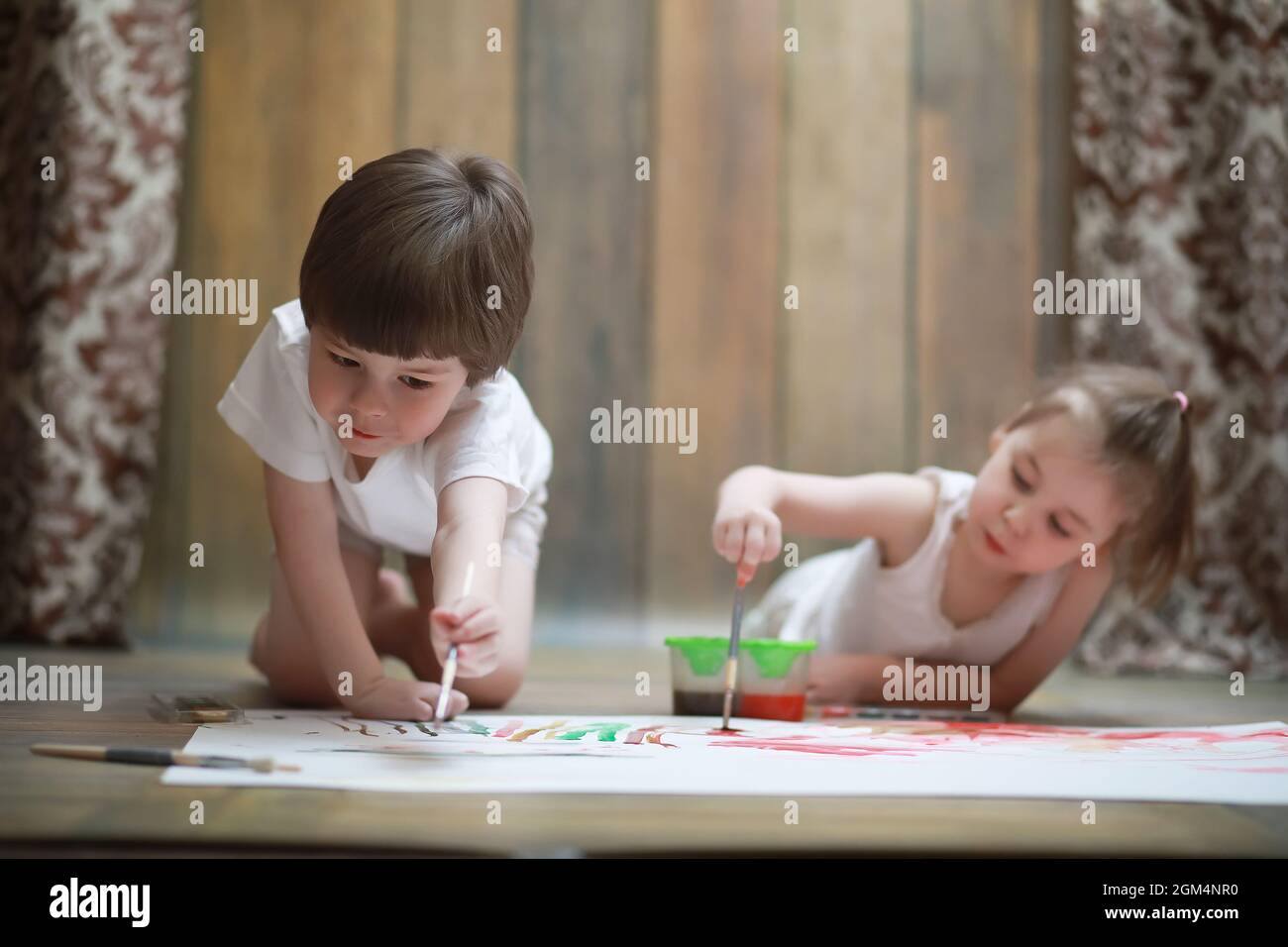 Little children paint on a large sheet of paper on the floor Stock ...
