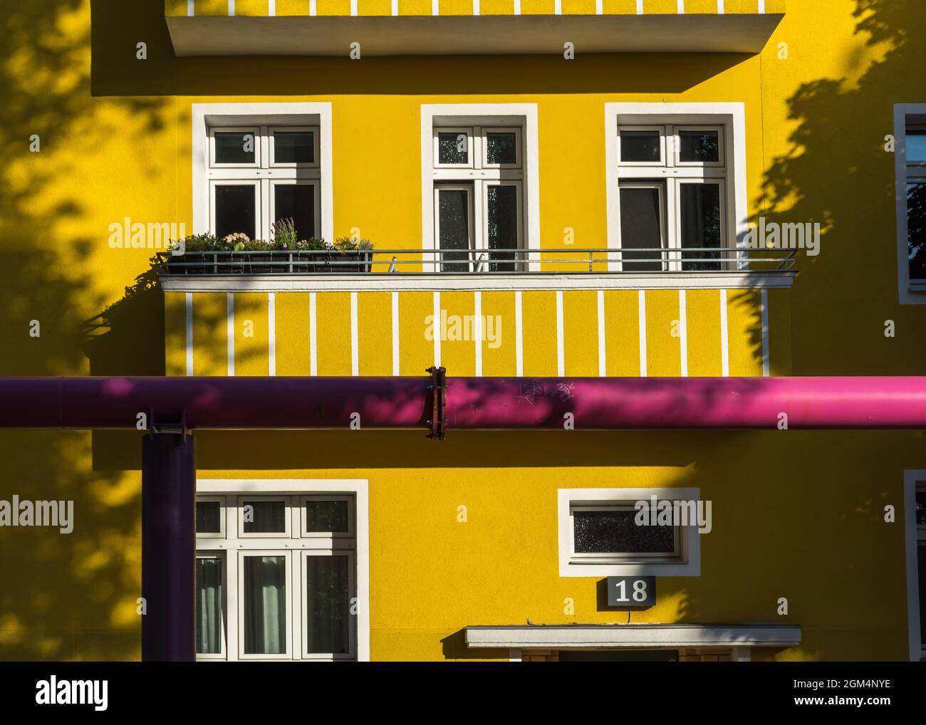 Yellow apartment building with a balcony and a pink water pipe Stock ...
