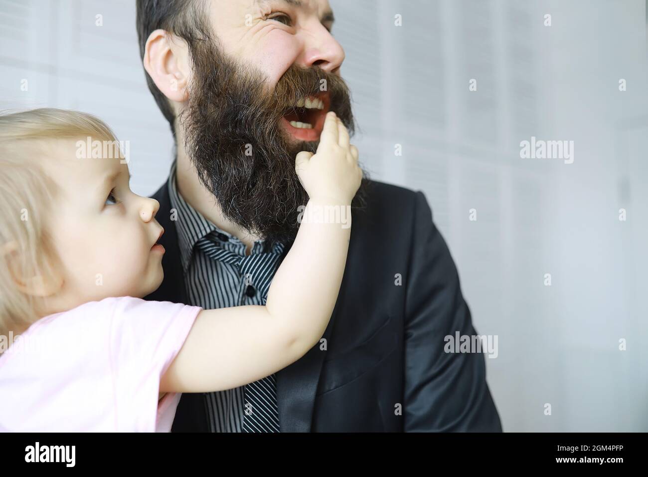 Baby infant hands grab beard of man.Cheerful hipster man curlers in a ...