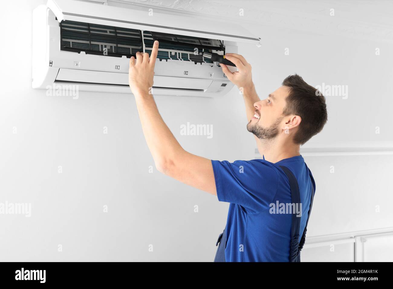 Male technician repairing air conditioner indoors Stock Photo - Alamy