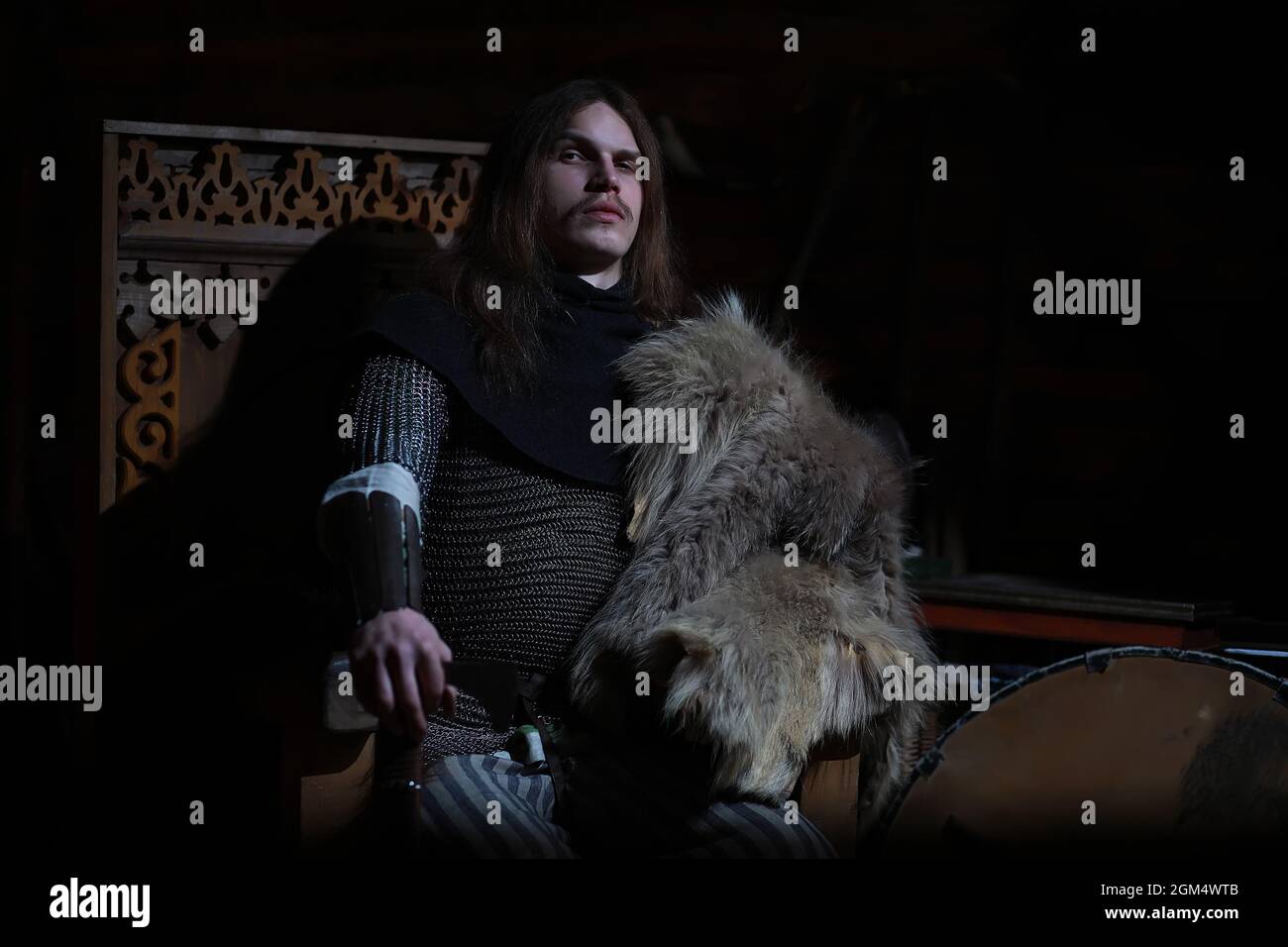 A mighty hero with long hair in chain mail armor in an ancient hall ...