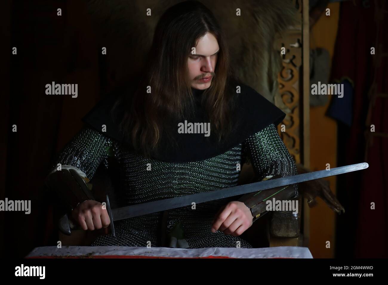 A mighty hero with long hair in chain mail armor in an ancient hall ...