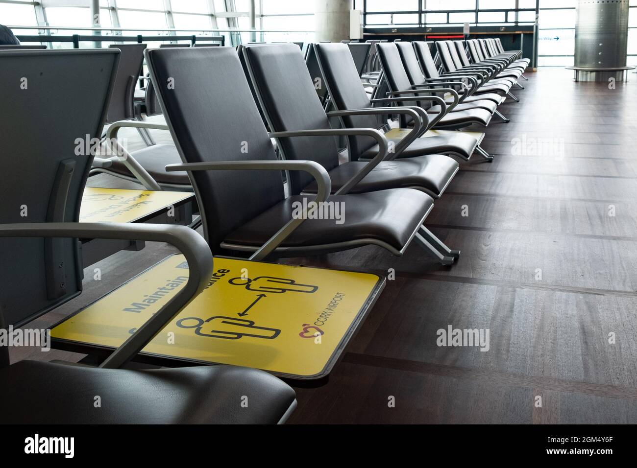 Yellow social distance sign on terminal chairs at airport. Safety ...