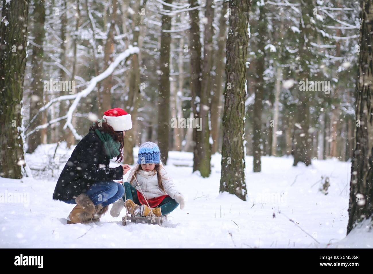 Winter fairy tale, a young mother and her daughter ride a sled in the ...