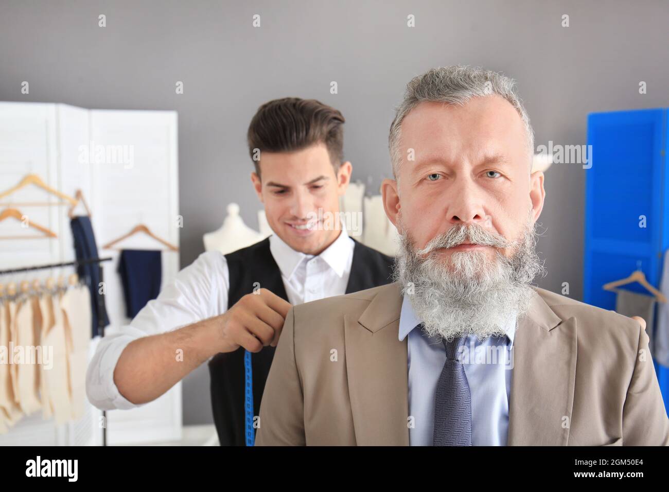 Tailor taking client's measurements in atelier Stock Photo - Alamy
