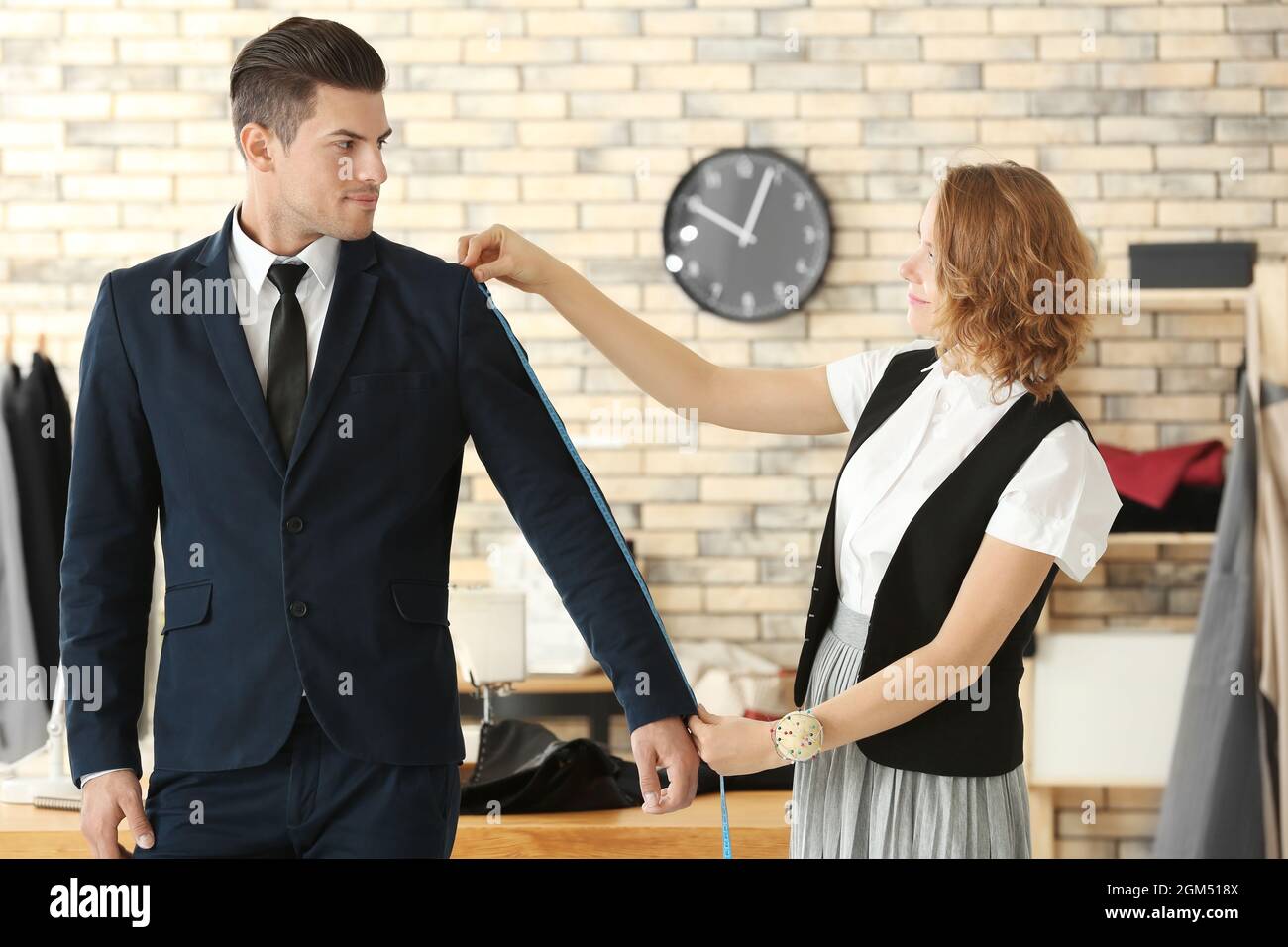 Seamstress taking client's measurements in atelier Stock Photo - Alamy