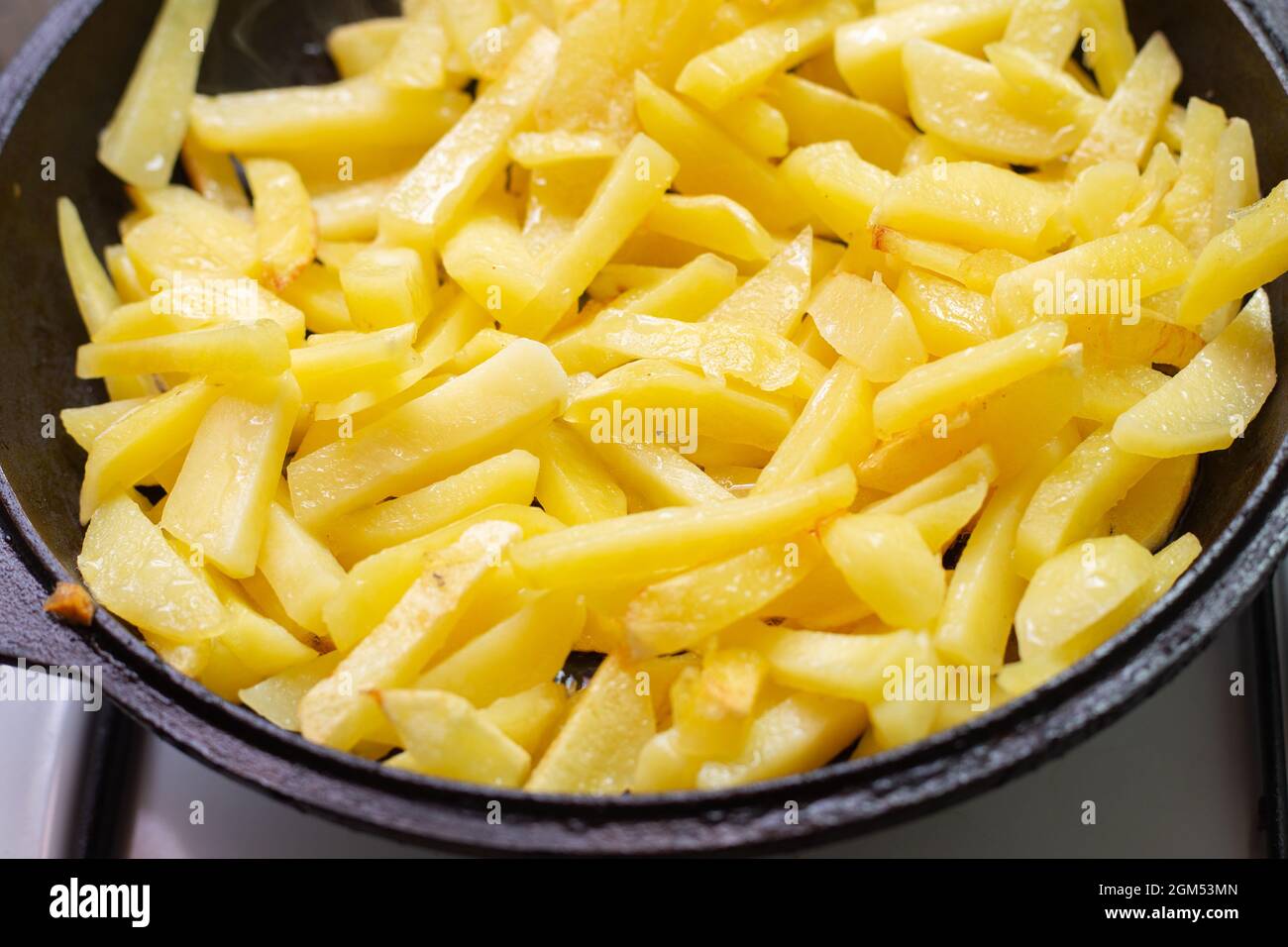 Potatoes cut into strips are fried in a pan. Delicious vegetable dish ...