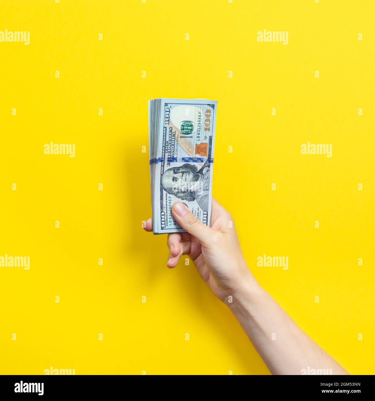 Hand holding a big stack of banknotes isolated on yellow background ...