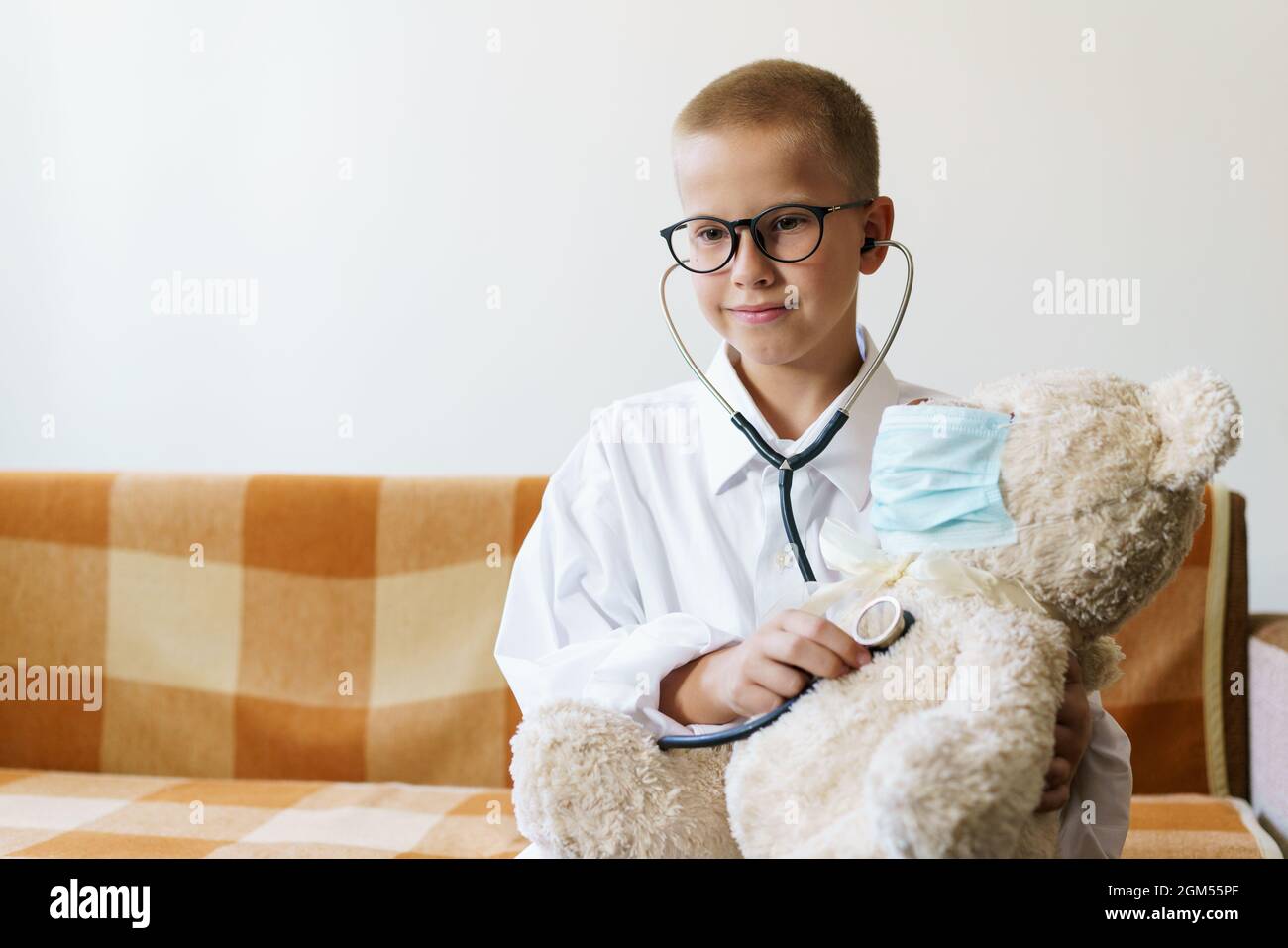 An adorable child dressed as a doctor plays with a teddy bear while ...
