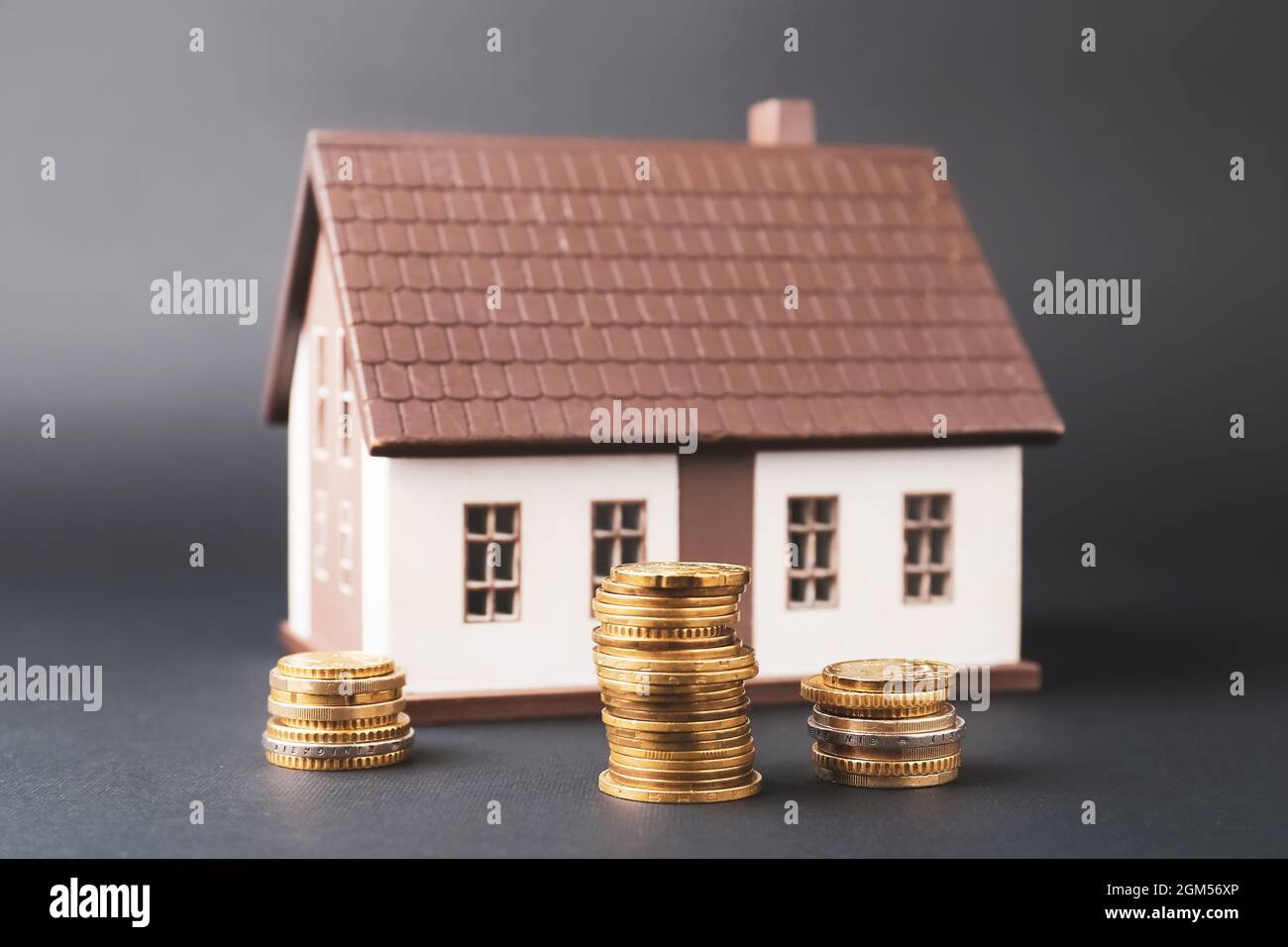 Model of house with coins on dark background Stock Photo - Alamy