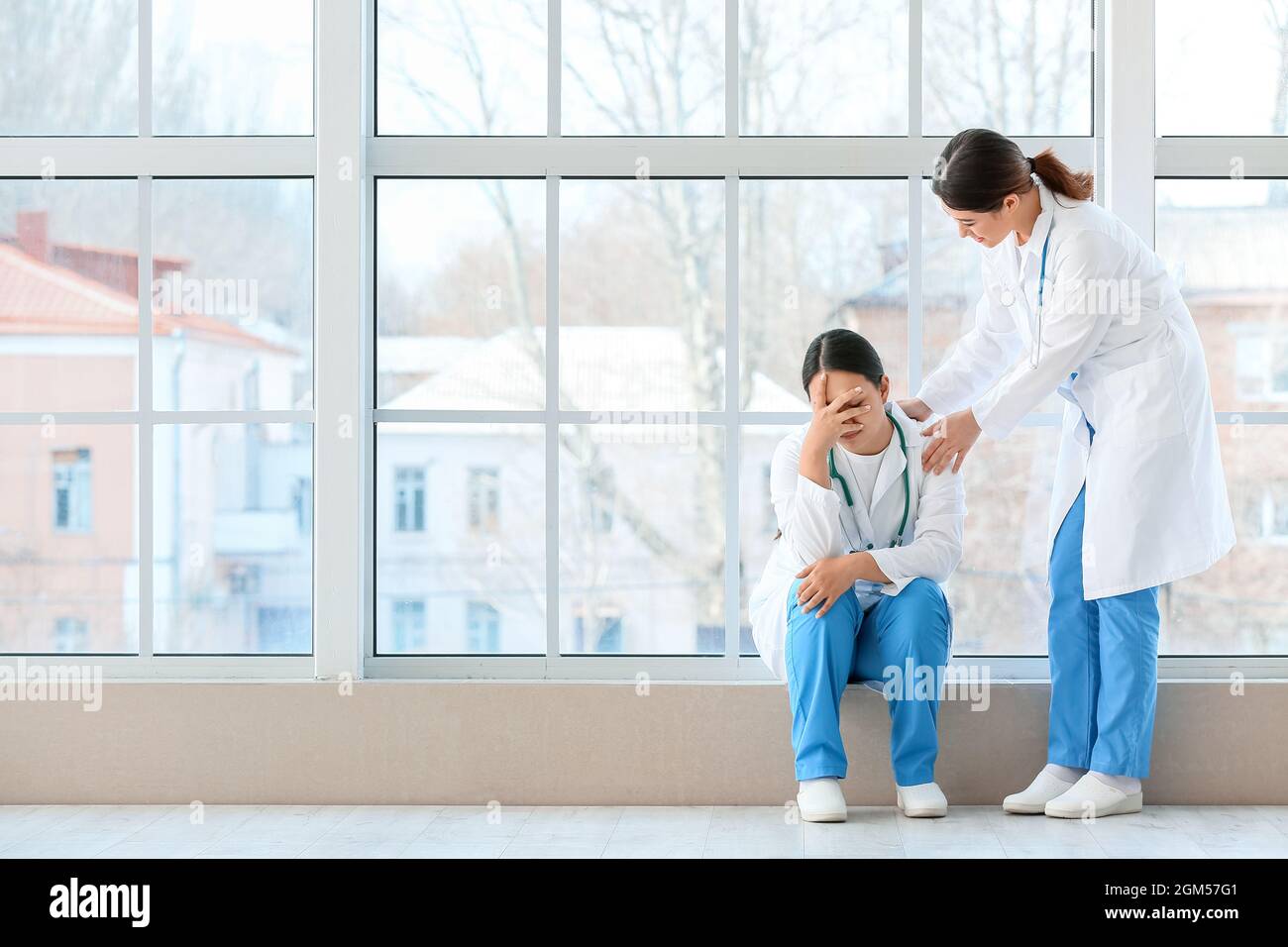 Female Asian doctor calming her colleague in hall of clinic Stock Photo ...