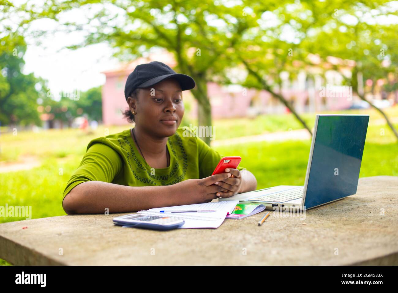 Pretty female student texting with her phone sitting at the table in ...