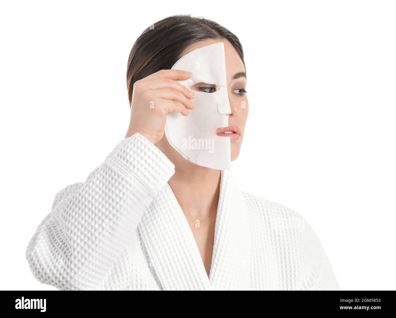 Beautiful young Asian woman with sheet facial mask on white background ...