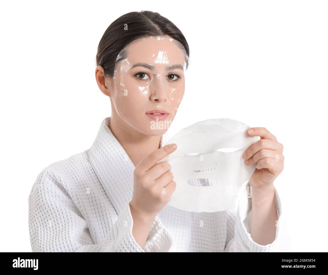 Beautiful young Asian woman with sheet facial mask on white background ...