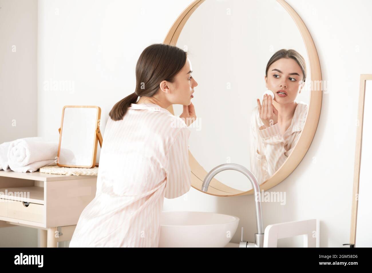Beautiful young woman removing makeup at home Stock Photo - Alamy