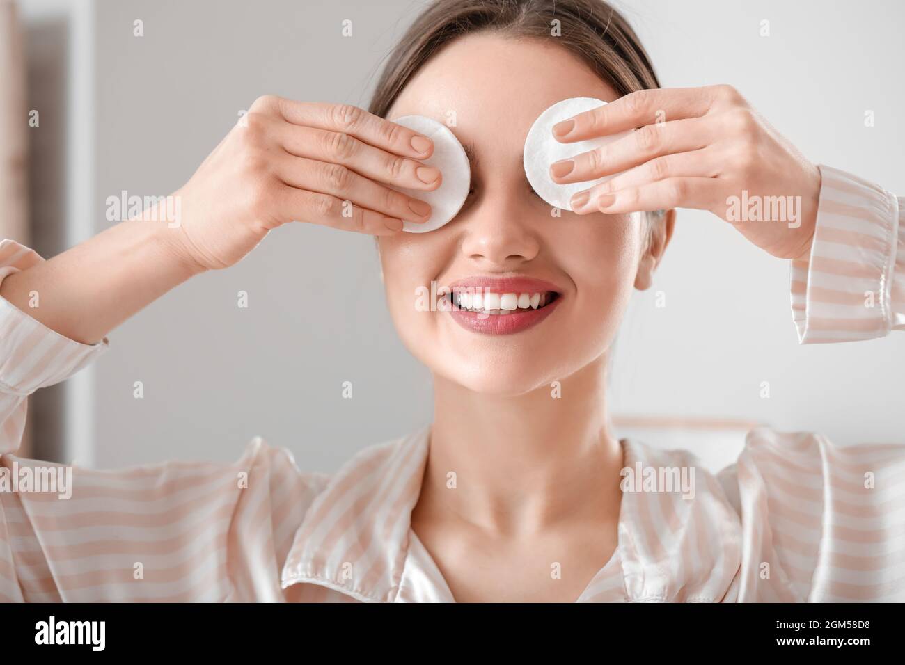 Beautiful young woman removing makeup at home Stock Photo - Alamy