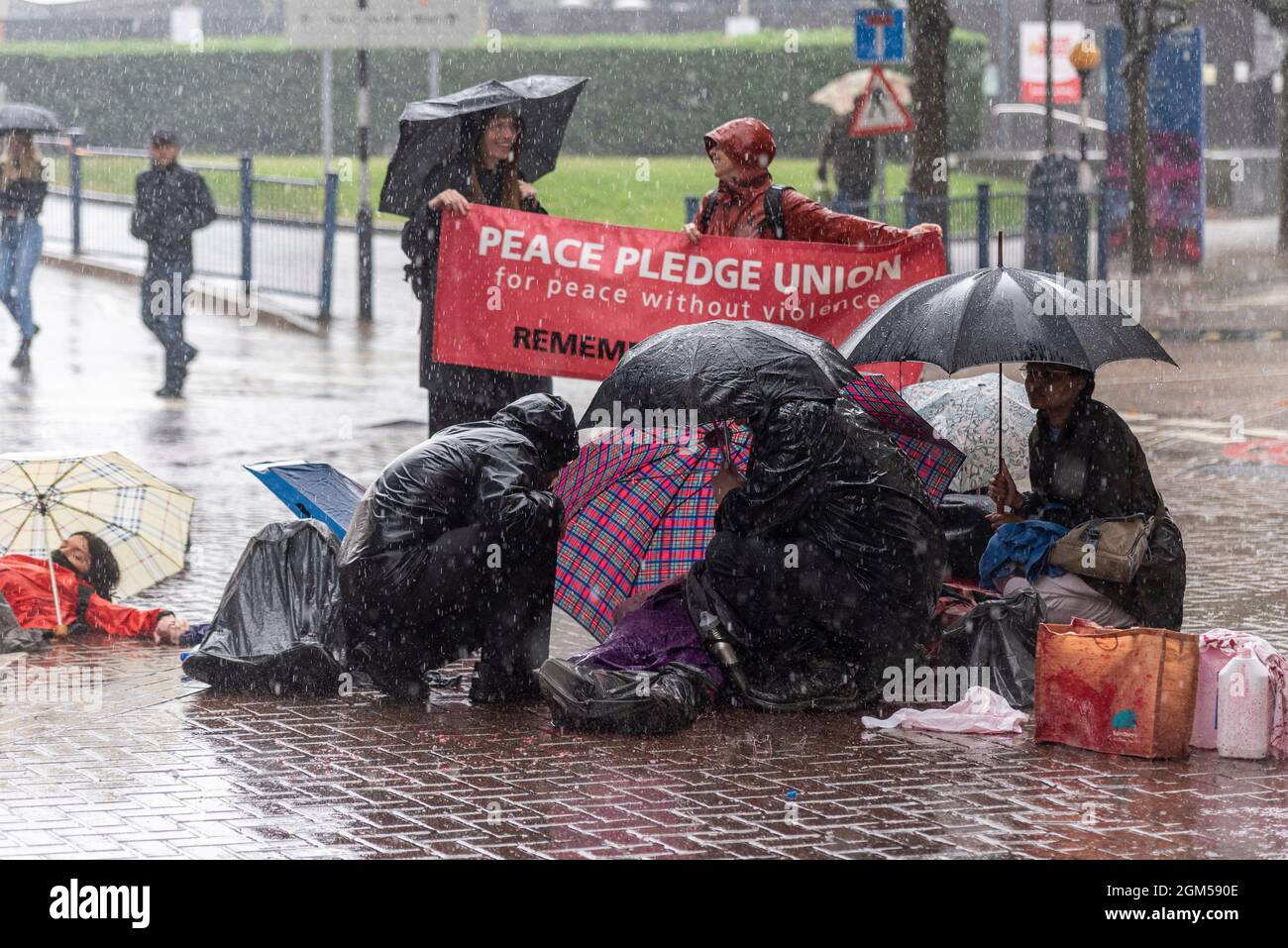 Protesters outside the DSEI arms fair huddled under umbrellas during a ...
