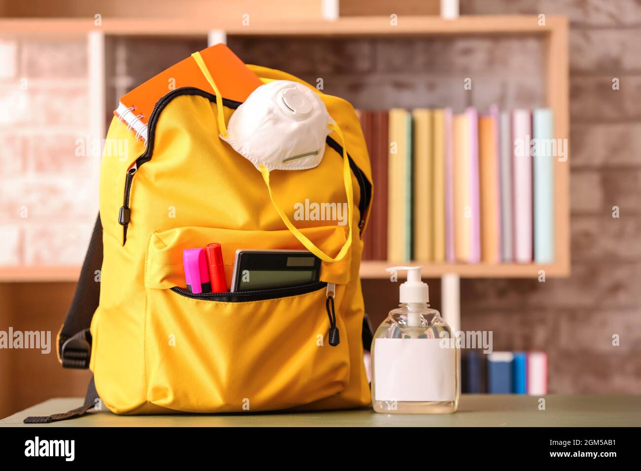 School backpack with stationery, bottle of sanitizer and respirator on ...