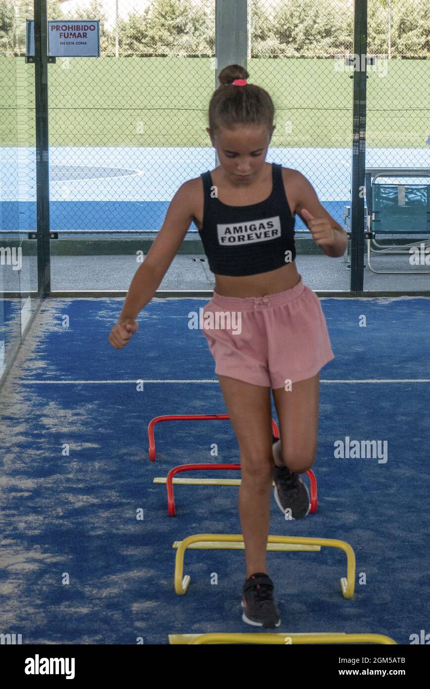 Young Caucasian teenage girl jumping over the colorful agility drills ...