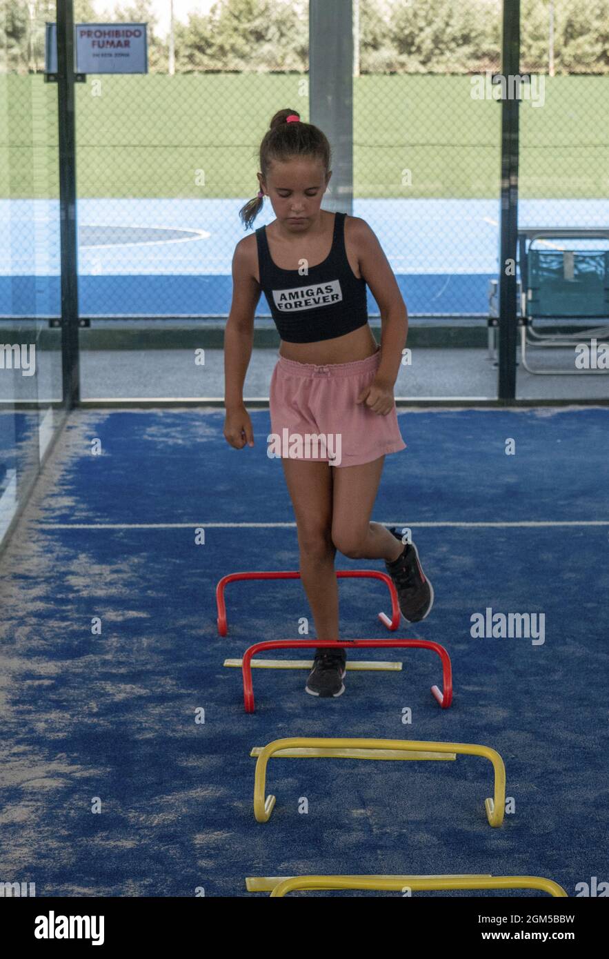 Young Caucasian teenage girl jumping over the colorful agility drills ...
