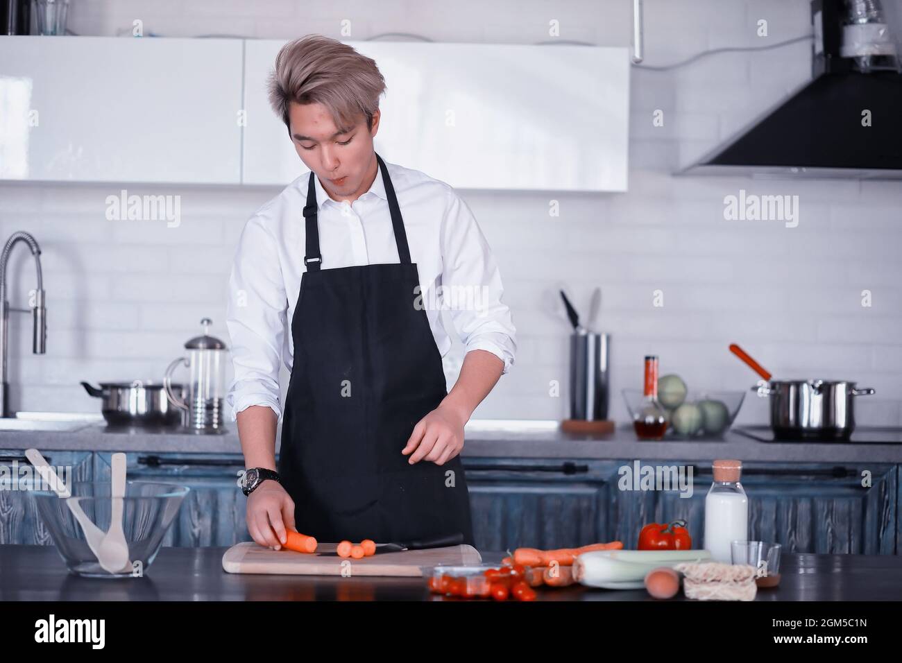 A young Asian cook in the kitchen prepares food in a cook suit Stock ...
