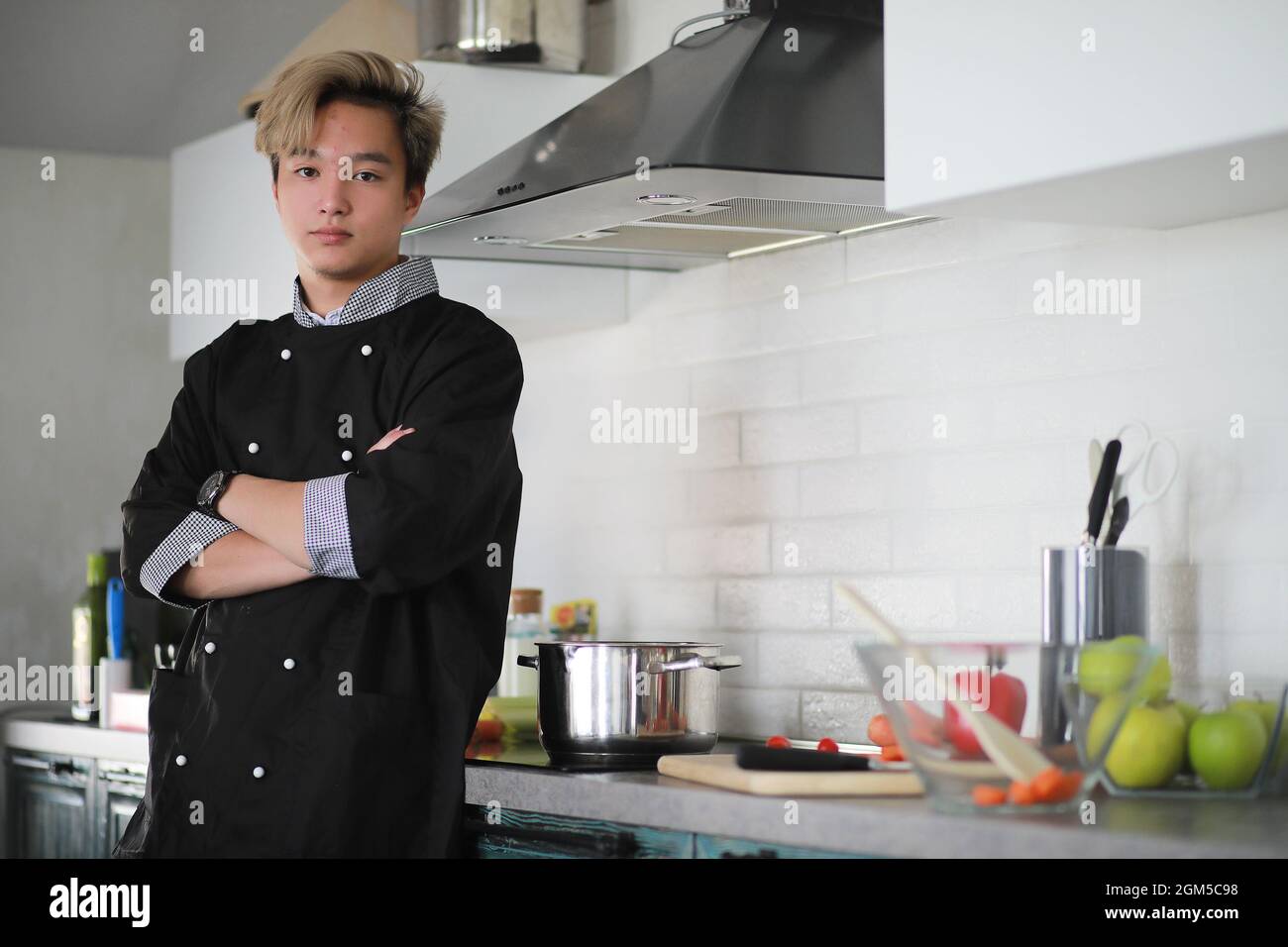 A young Asian cook in the kitchen prepares food in a cook suit Stock ...