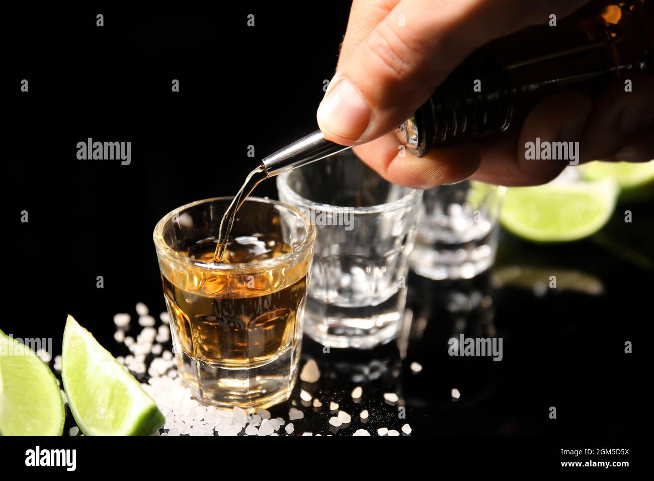 Bartender pouring tasty tequila into shots on dark background, closeup ...