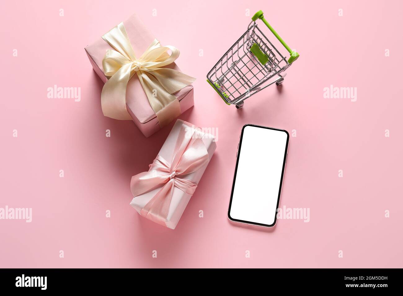 Shopping cart, phone and gift boxes on color background Stock Photo - Alamy