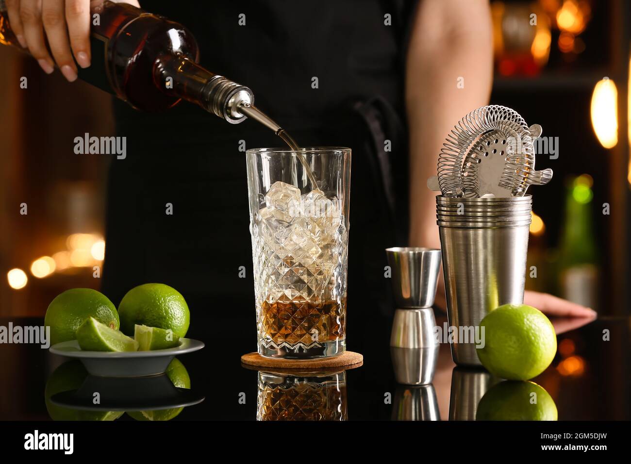Female bartender making refreshing Long Island iced tea on table in bar ...