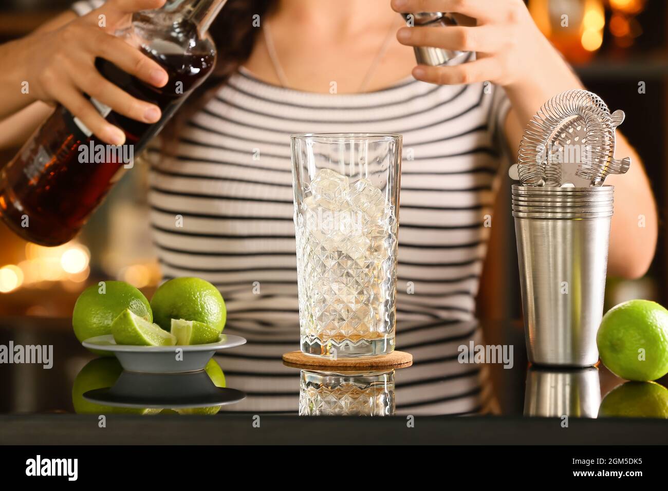 Female bartender making refreshing Long Island iced tea on table in bar ...