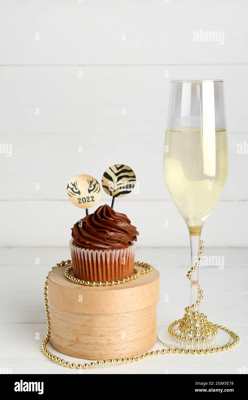 Tasty cupcake for New Year 2022 celebration and glass of champagne on ...