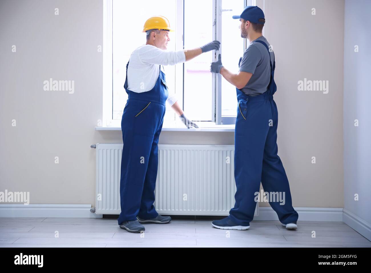 Construction worker with trainee installing window in house Stock Photo ...