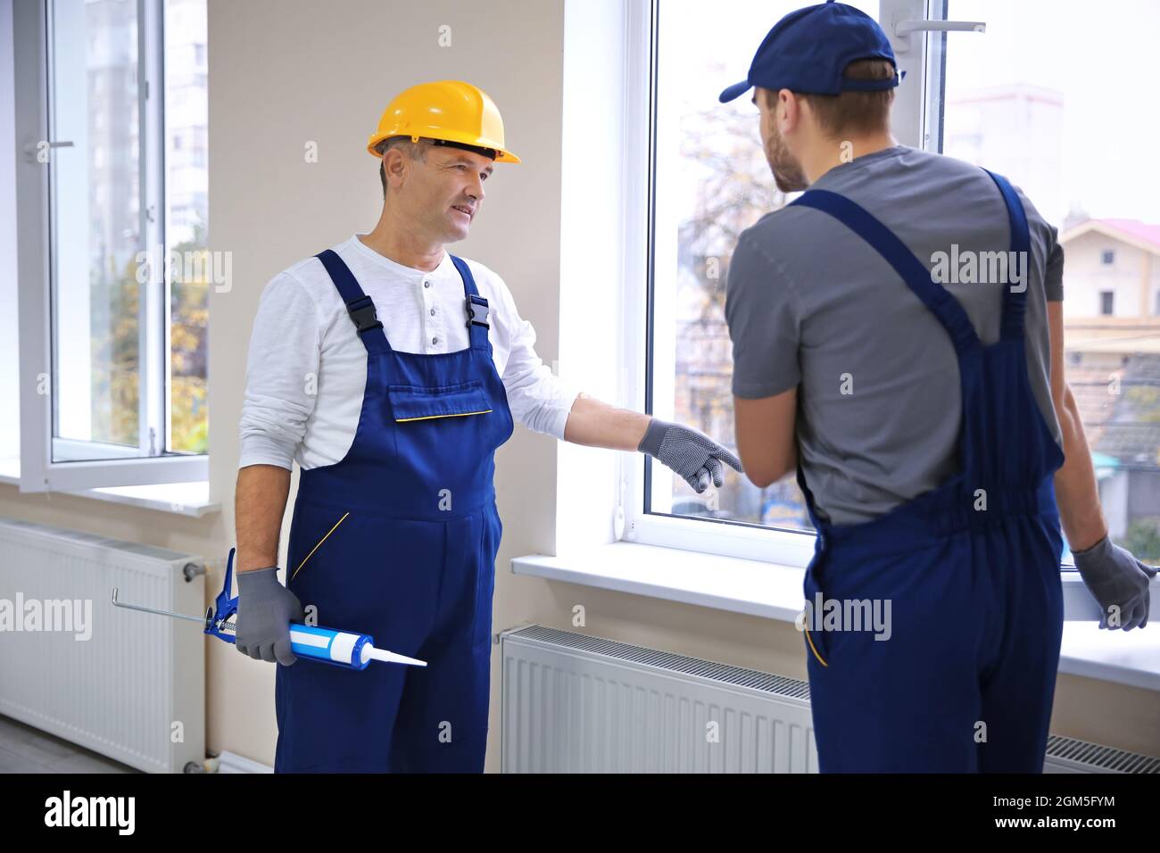 Construction worker with trainee installing window in house Stock Photo - Alamy