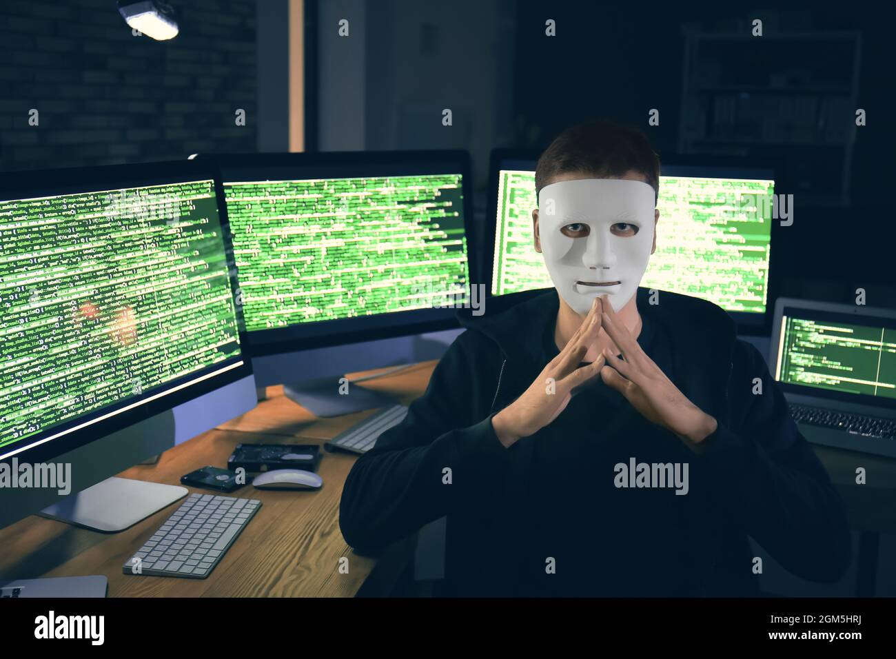 Masked hacker in dark room with computers. Threat of cyber attack Stock ...