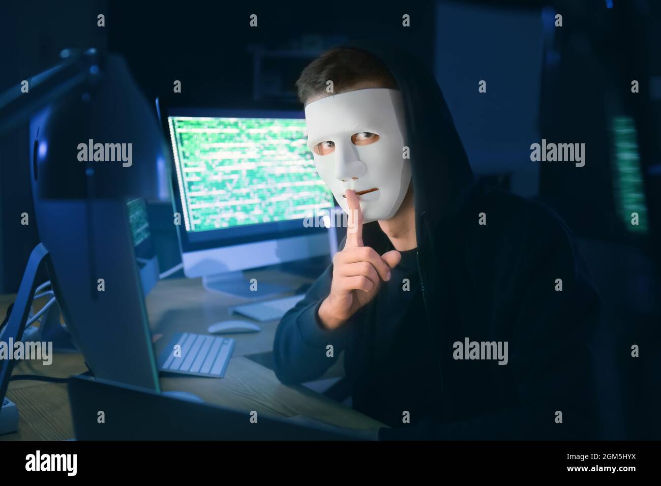 Masked hacker in dark room with computers. Threat of cyber attack Stock ...