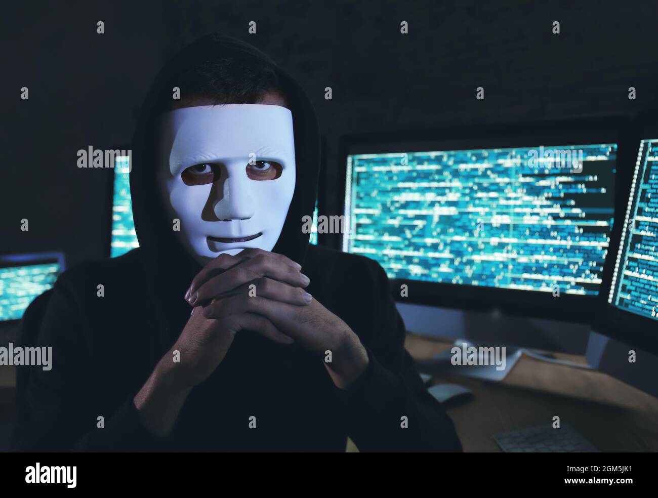 Masked hacker in dark room with computers. Threat of cyber attack Stock ...
