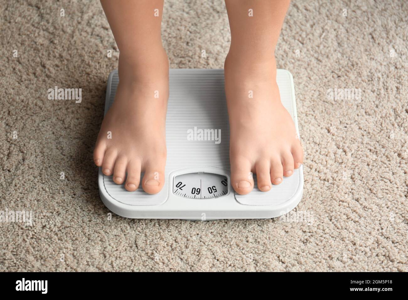 Overweight boy using scales at home Stock Photo - Alamy