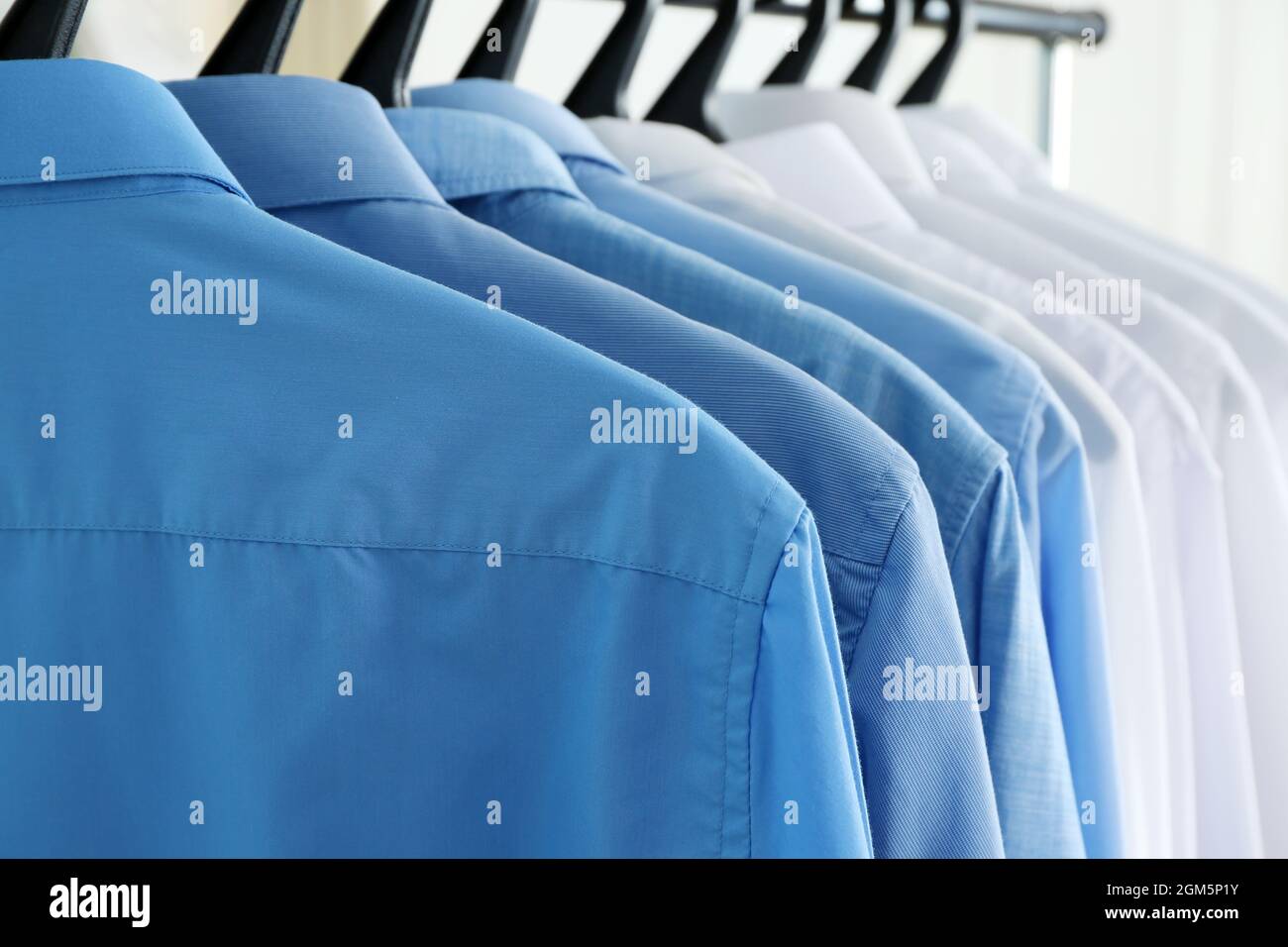 Clean shirts hanging on rack in laundry, closeup Stock Photo - Alamy